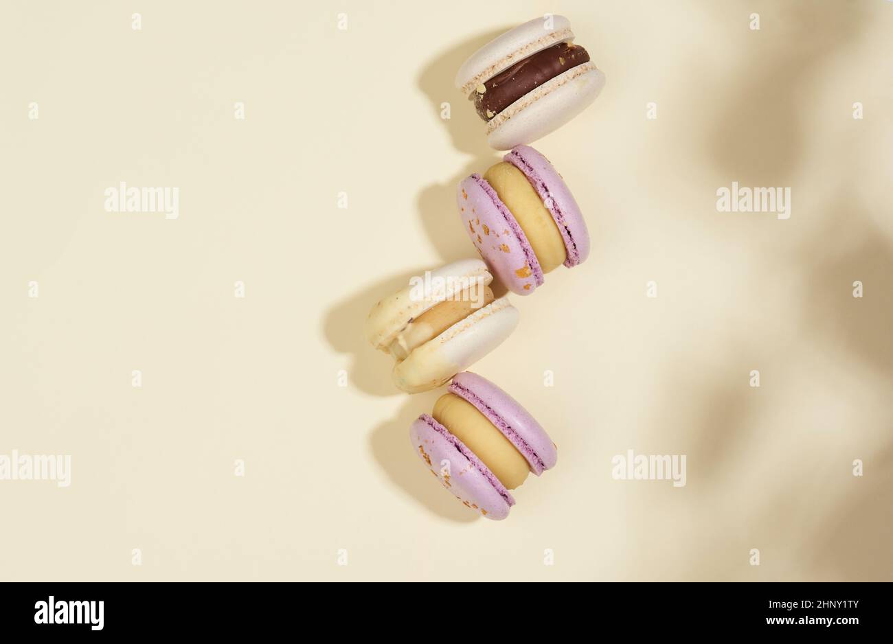 baked macarons with different flavors on a beige background, top view ...