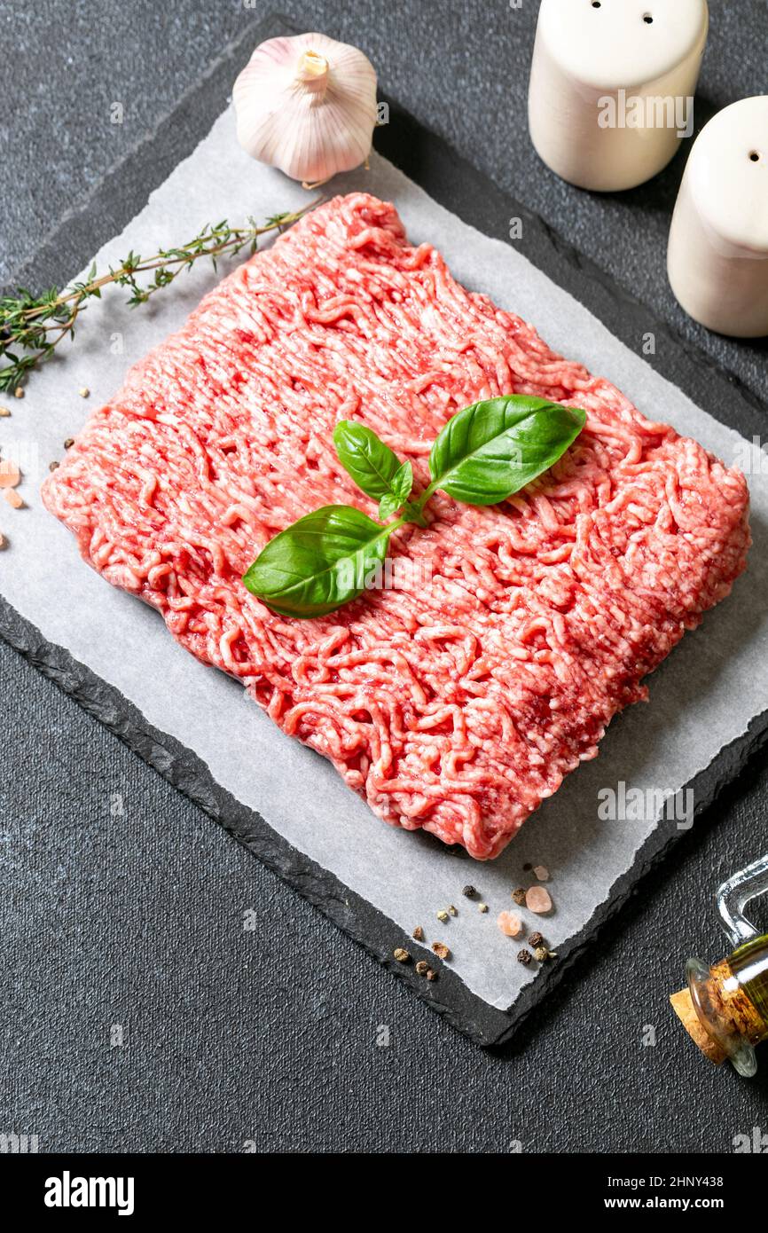 fresh raw minced meat on paper and black slate cutting board, on gray ...