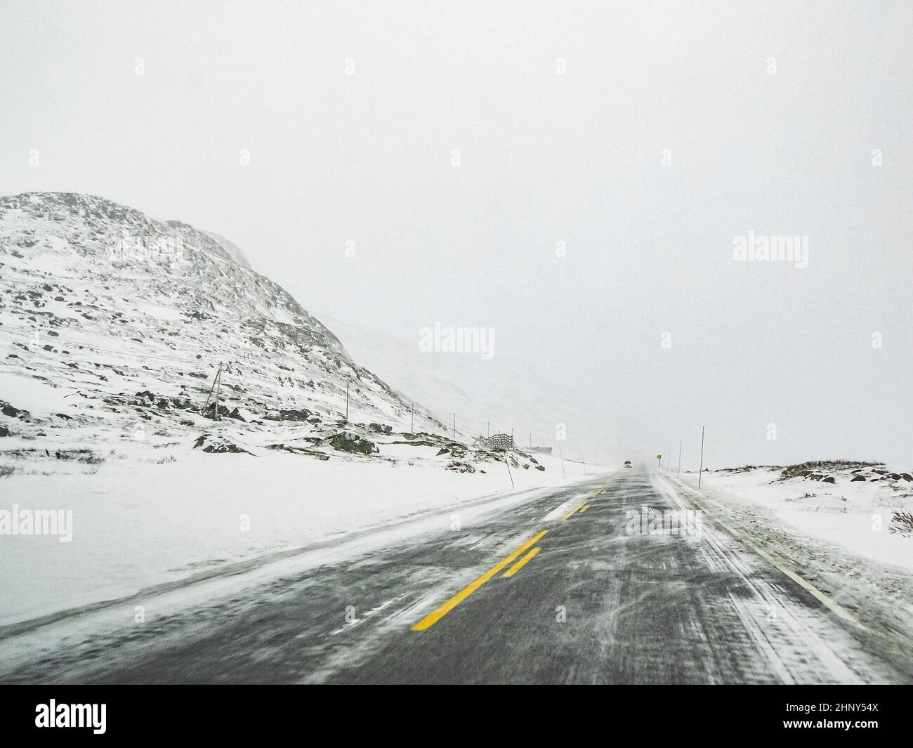 Driving through blizzard snowstorm on black ice and snowy white road ...