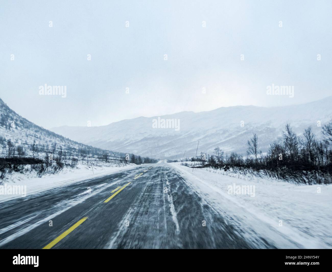 Driving through blizzard snowstorm on black ice and snowy white road ...