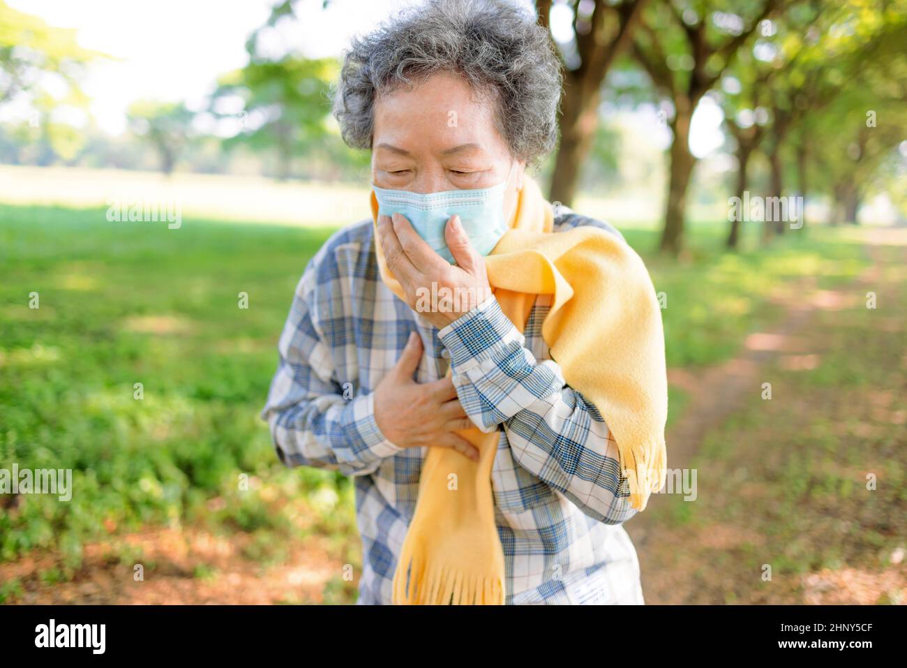 senior woman coughing into her hand while clutching her chest Stock ...