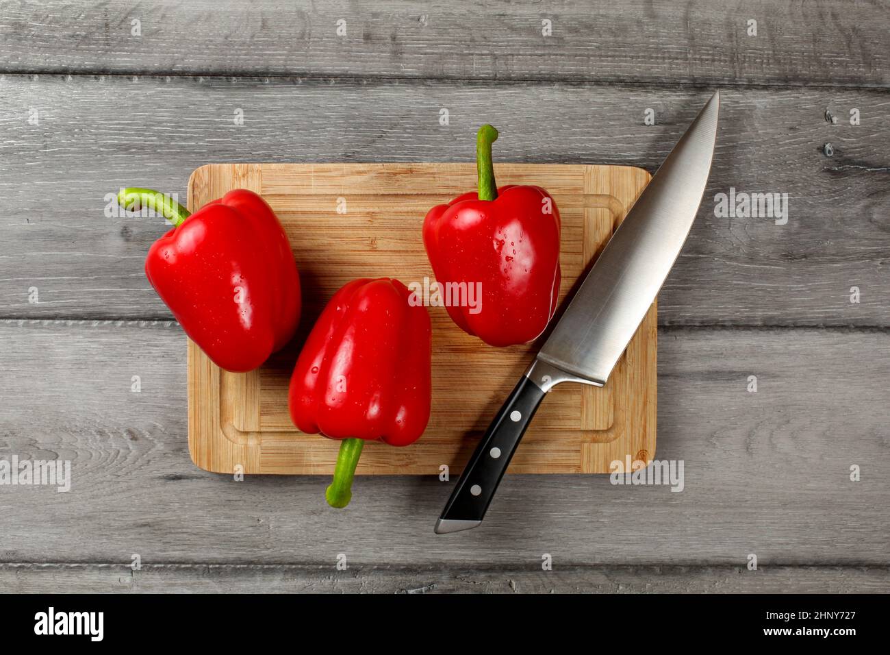 Table top view - three bright red bell peppers, water drops, with chefs ...