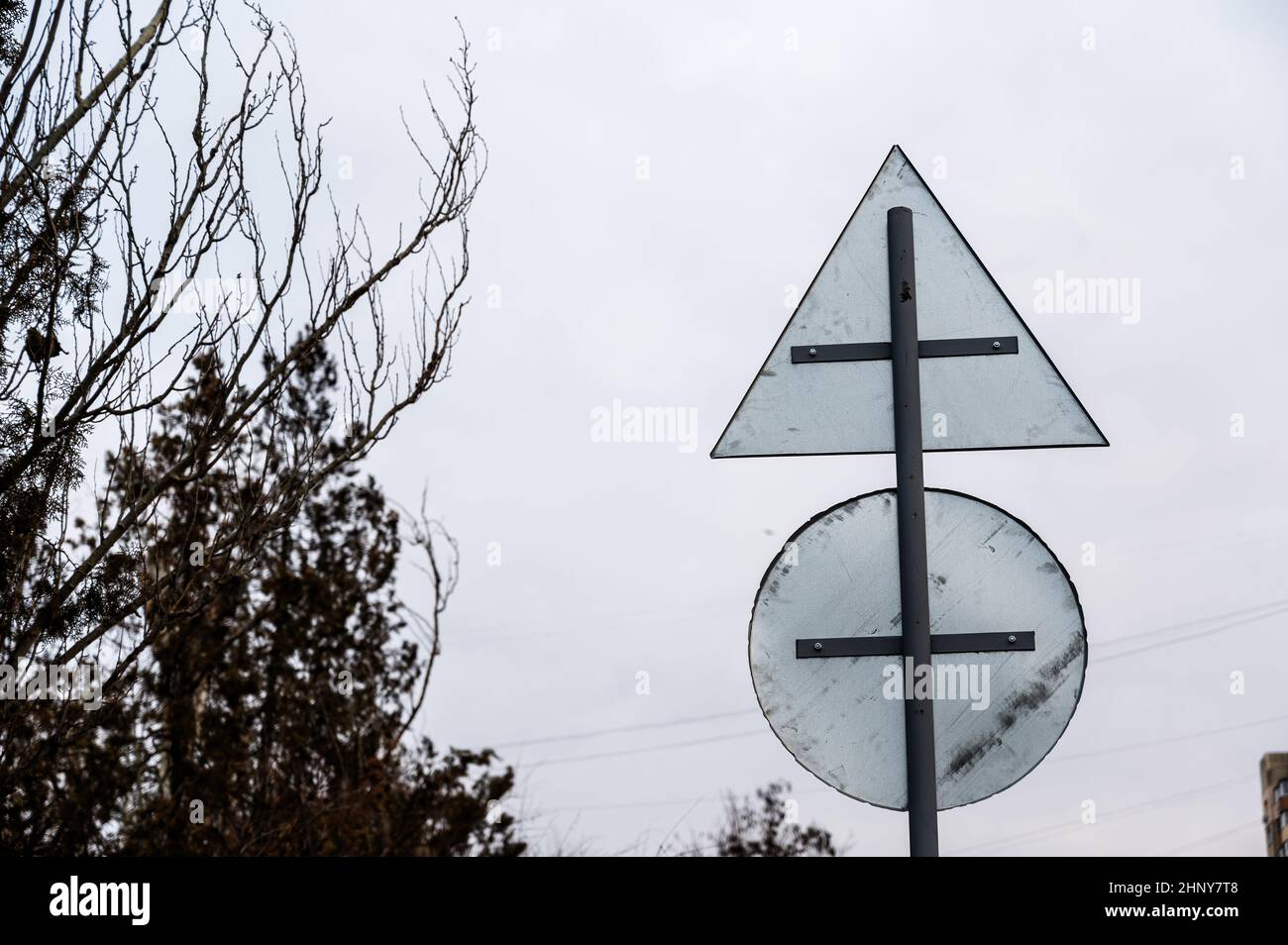 Road signs, backside. Circular and triangular sign opposite overcast ...