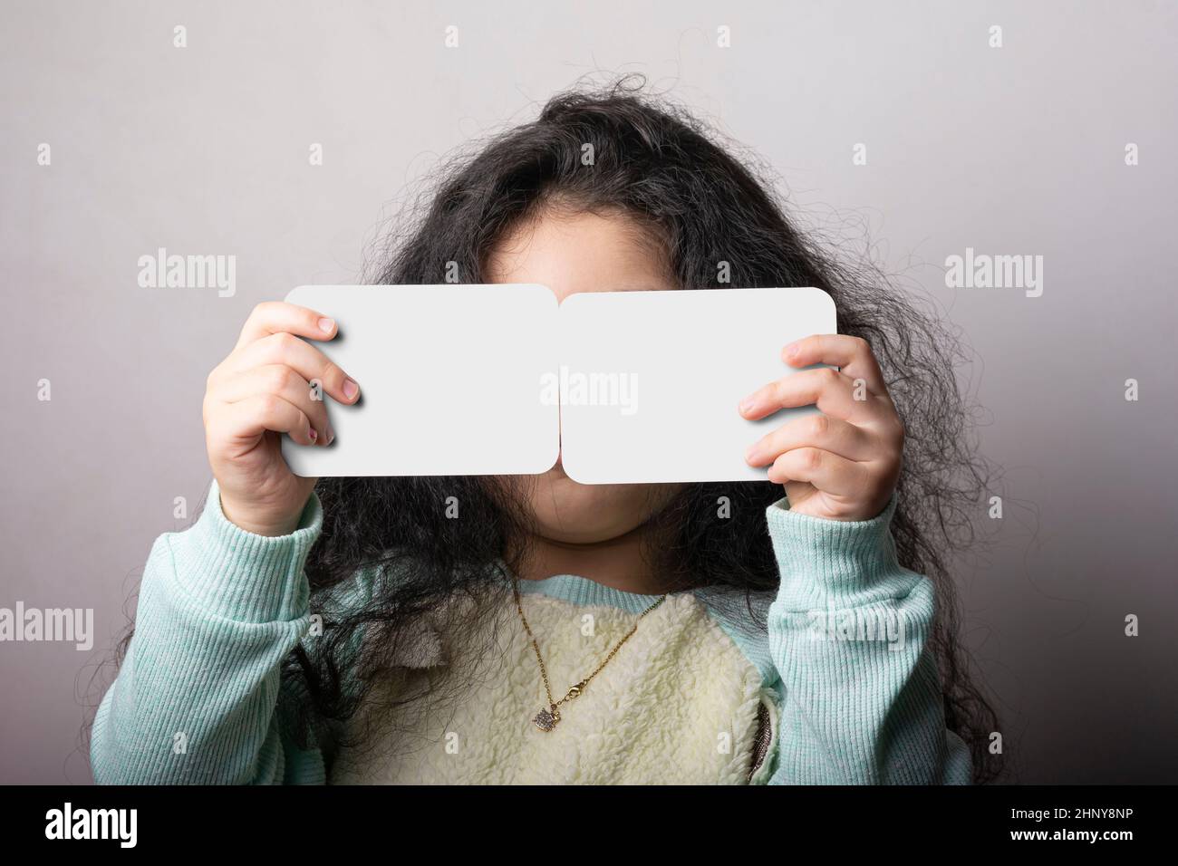 Little girl portrait holding two flash card in front of face ...