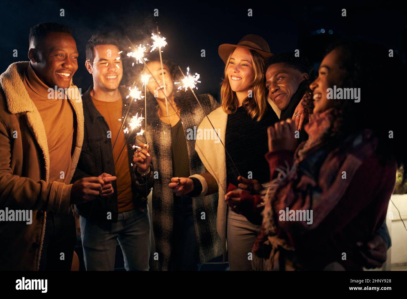 Diverse group of multi-cultural young adults at a party lighting ...