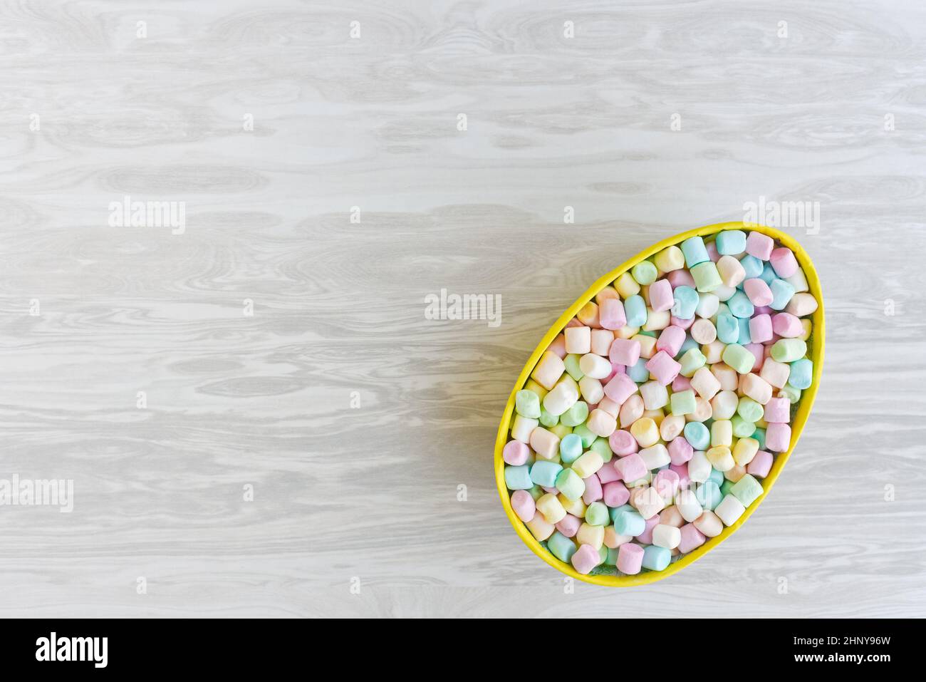 Decorative Easter egg and multi colored mini marshmallows on white ...