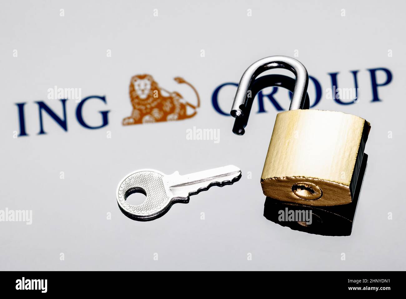 An open security lock and key on background of ING Group logo in mirror ...
