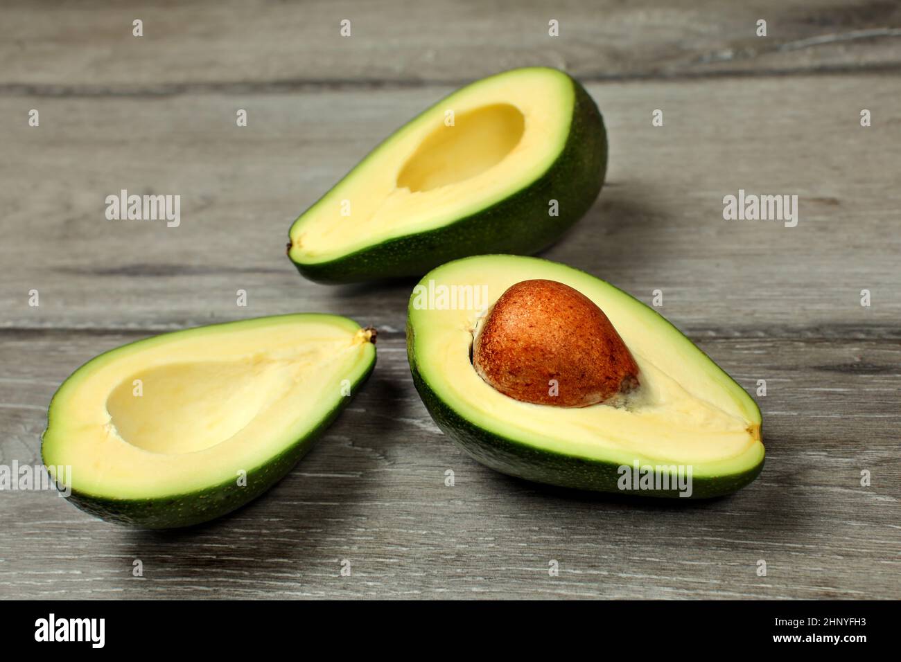 Avocado, cut in half on gray wood table Stock Photo - Alamy