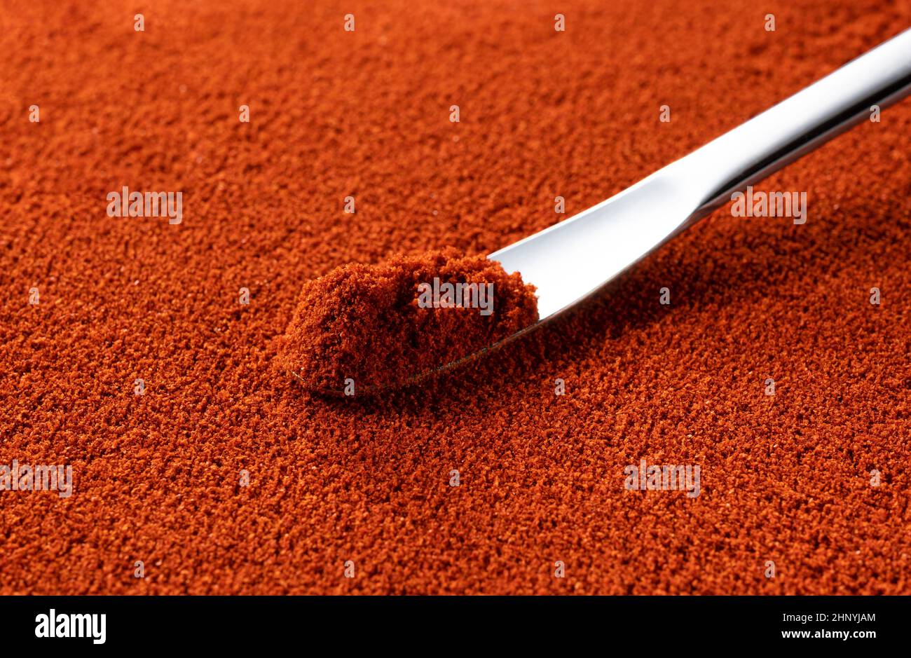 Red pepper powder spread all over and a silver spice spoon on top of it ...