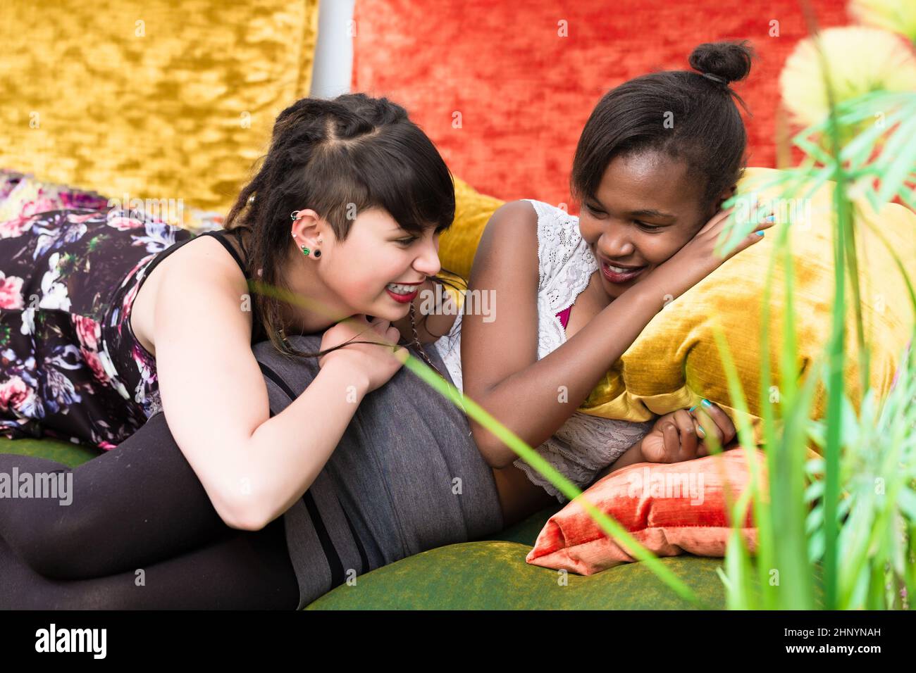 Smiling woman leaning on friends lap relaxing on sofa Stock Photo - Alamy