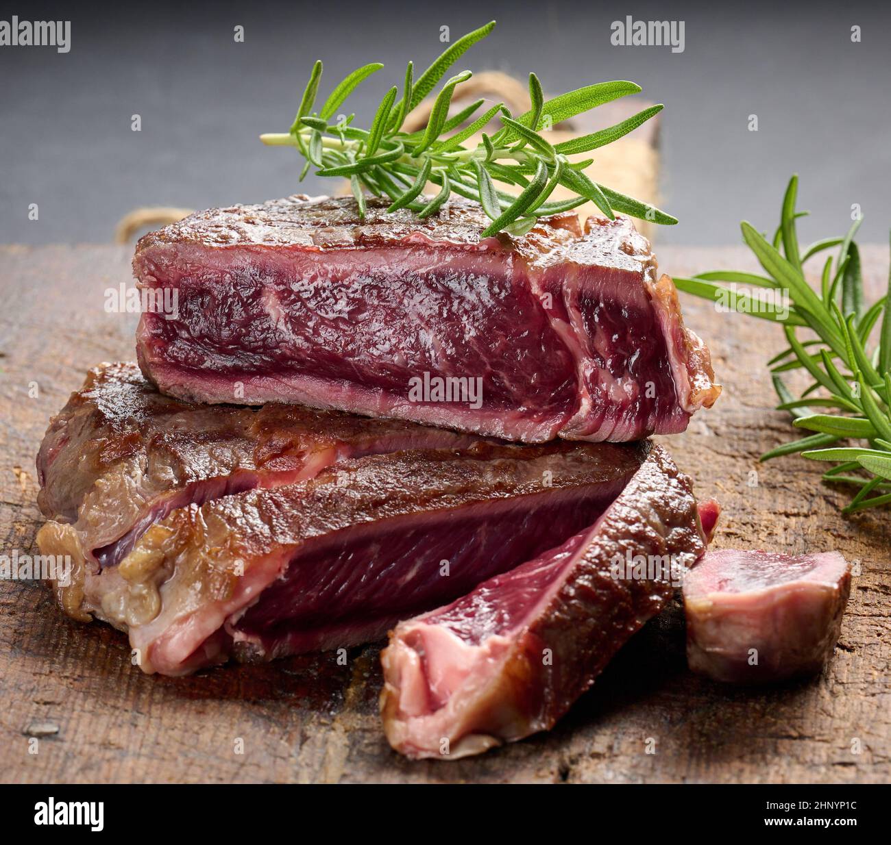 fried piece of beef ribeye, cut into pieces on a brown wooden board ...