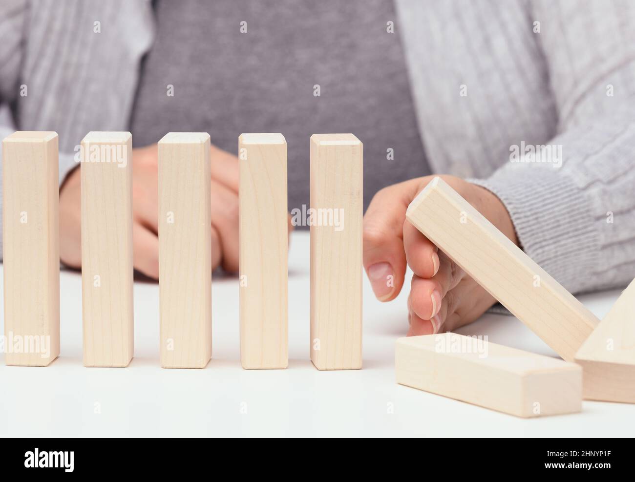 hand stops the fall of wooden blocks on a white background. Concept of ...