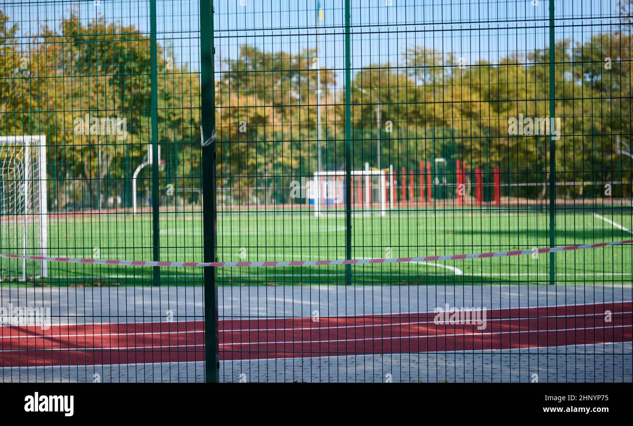red and white prohibitory tape on the fence of the sports complex ...