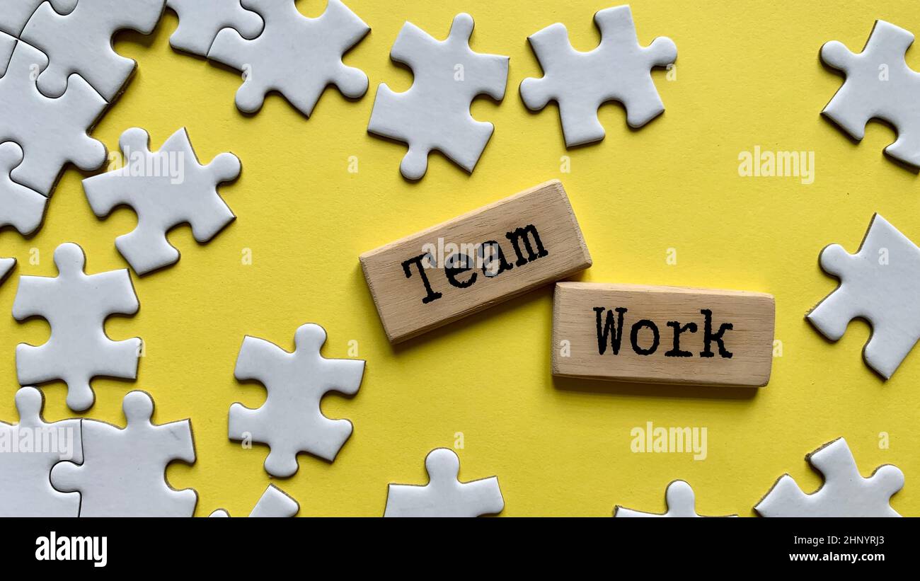 Wooden blocks with words - Team work. Jigsaw puzzle and yellow desk ...