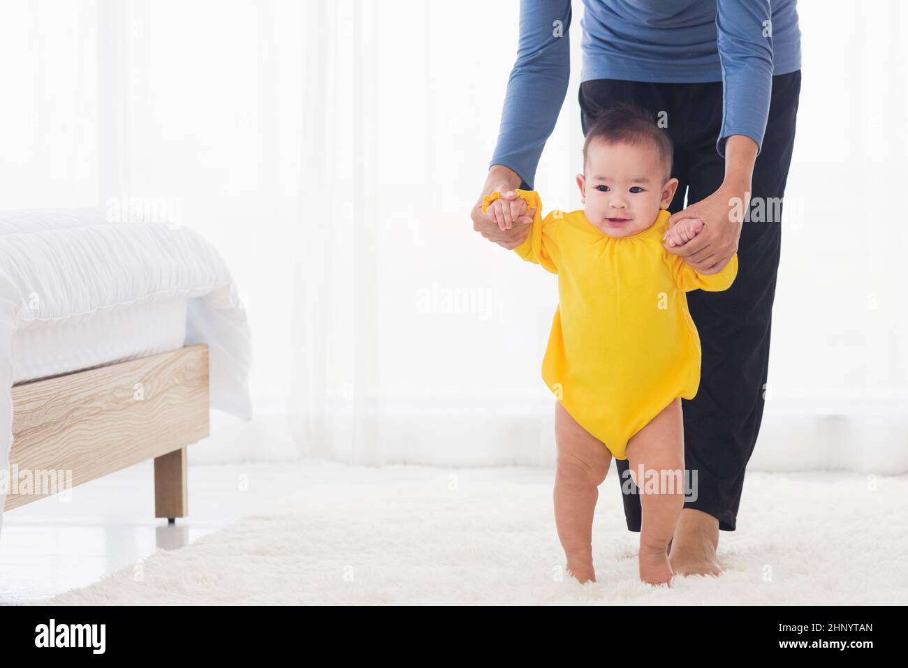 Asian little baby taking first steps learning to walk with mother help ...