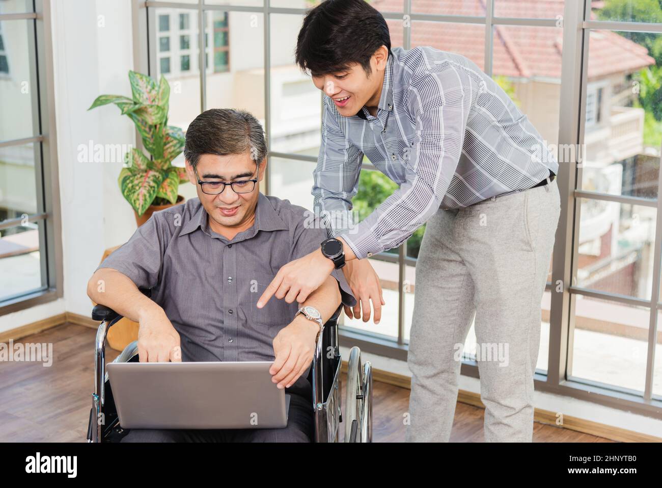 Asian senior disabled businessman in a wheelchair with laptop computer ...