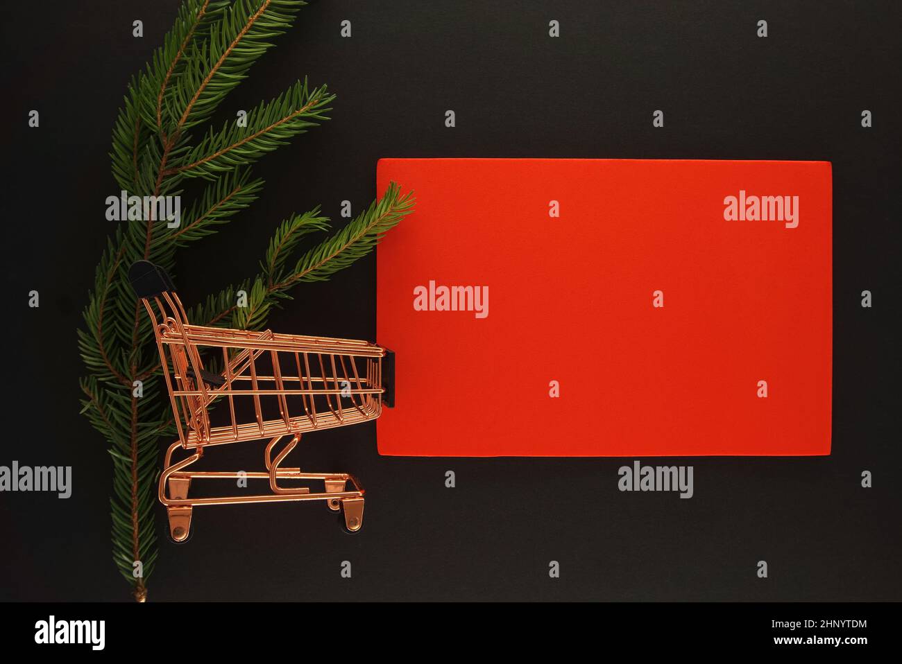 Fir branch and golden shopping cart on black background with red banner ...