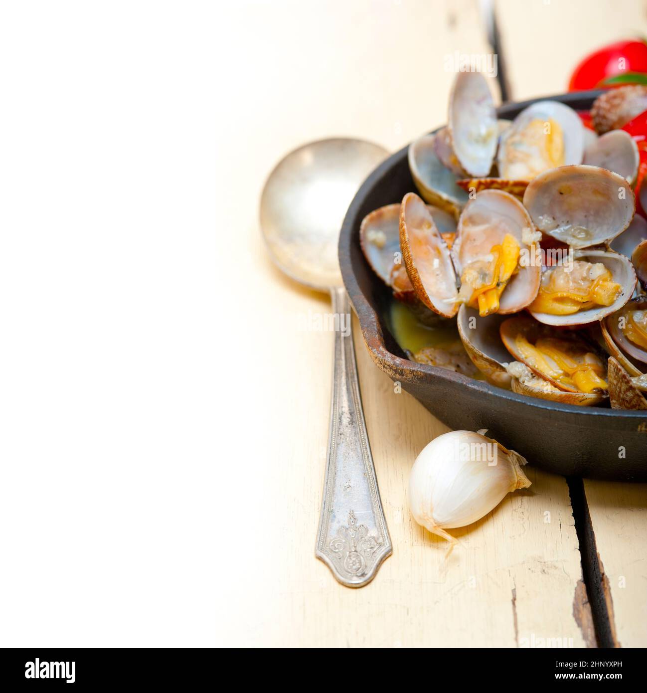 fresh clams stewed on an iron skillet over wite rustic wood table Stock ...
