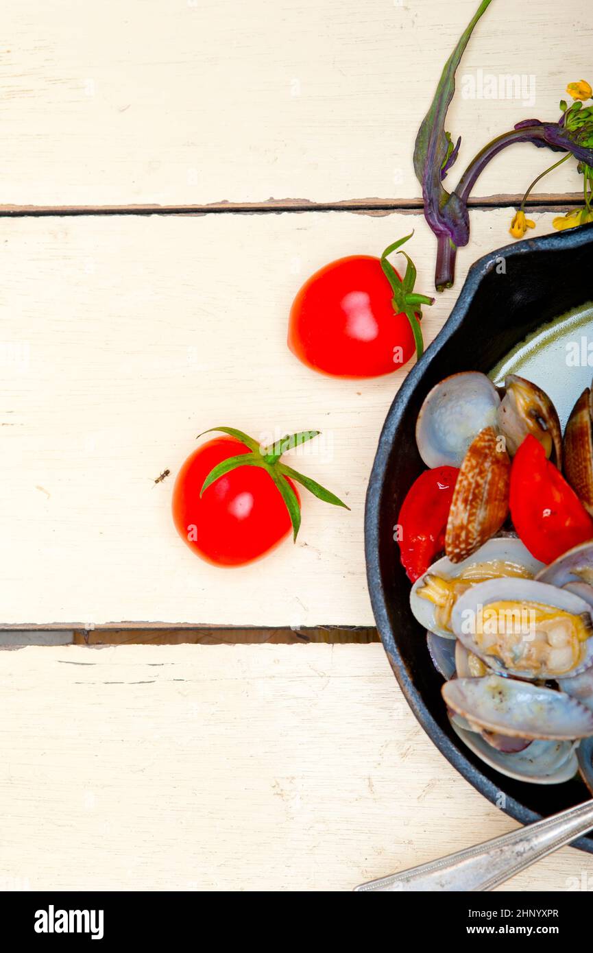 fresh clams stewed on an iron skillet over wite rustic wood table Stock ...