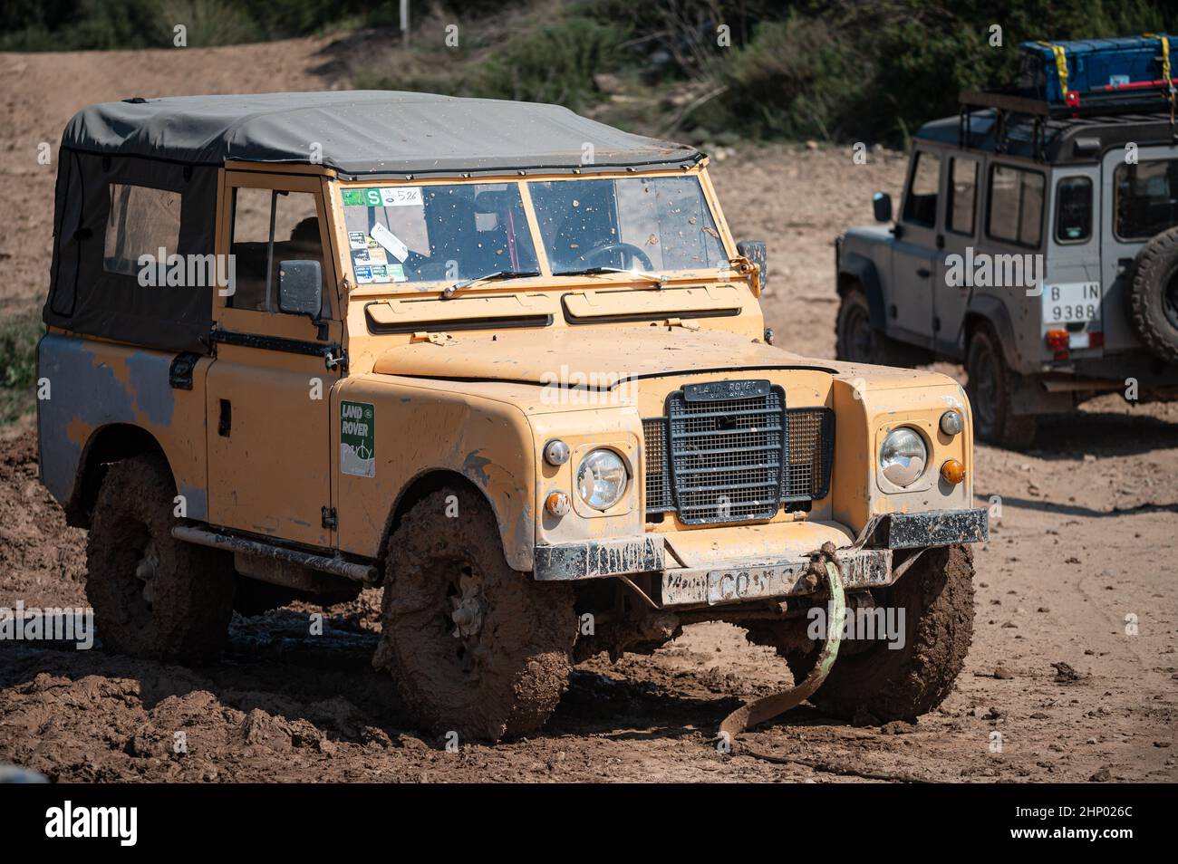 Old yellow Land Rover Santana being towed with a rope on a muddy road ...
