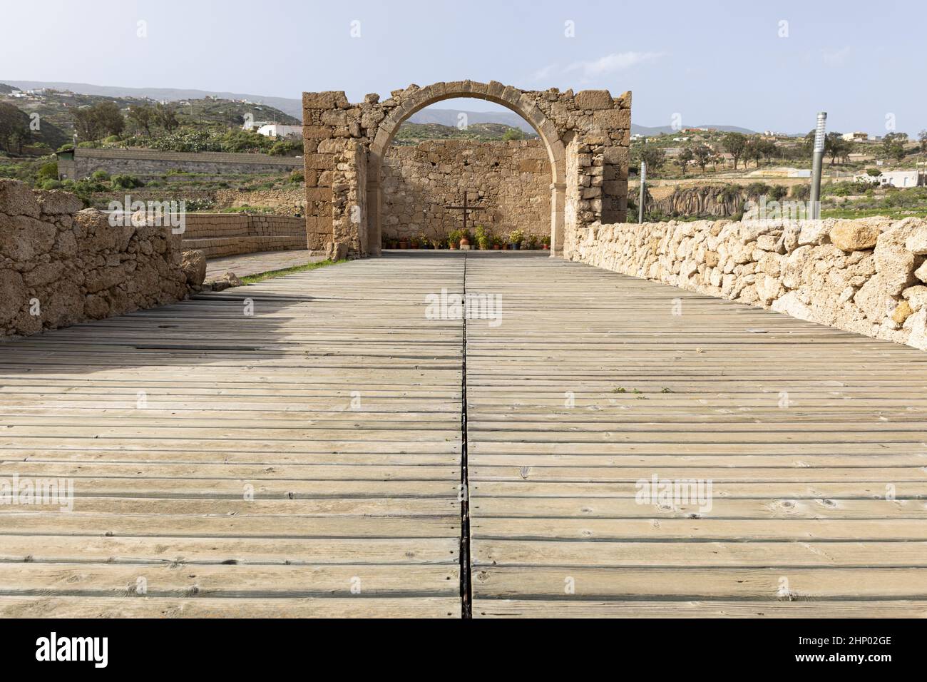 Ruins of an ancient building and an arch with a wooden floor and metal ...