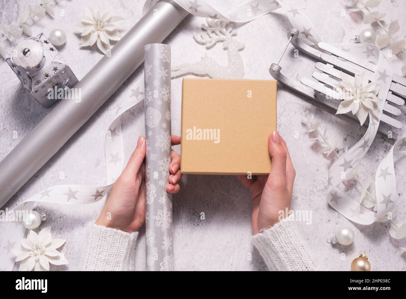 Female hands hold a gift box for packaging in silver and white for ...