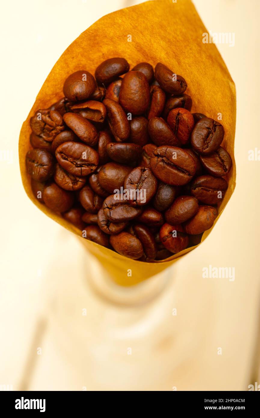 espresso coffee beans on a paper cone cornucopia over white background ...