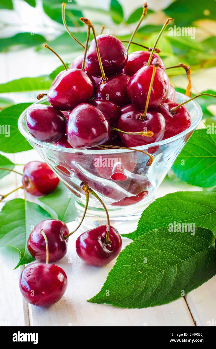 Ripe and fresh burgundy cherries in a glass vase and a jar for healthy ...