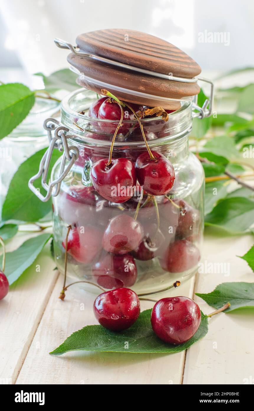 Ripe and fresh burgundy cherries in a glass vase and a jar for healthy ...