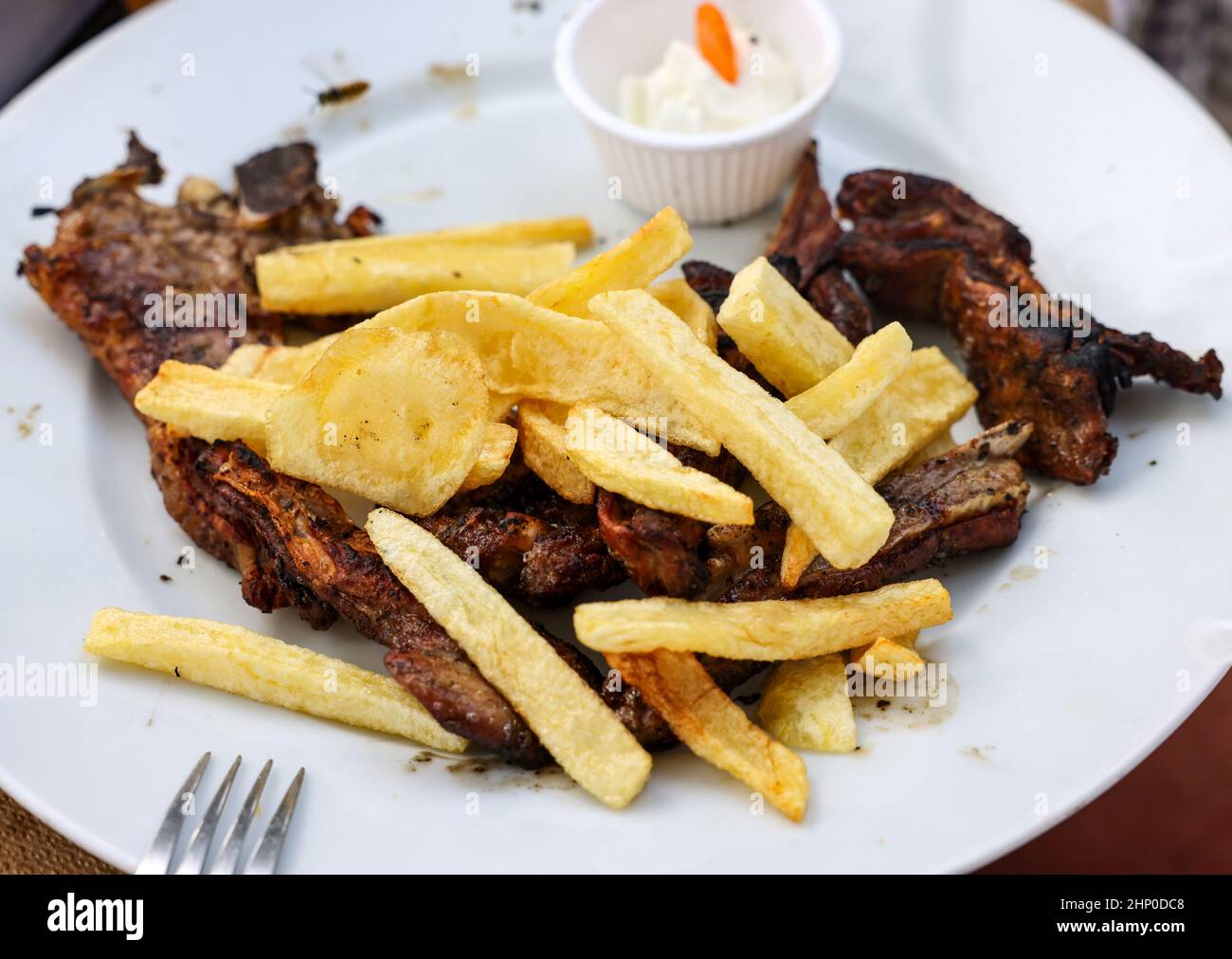 grilled goat with fries on a white plate Stock Photo - Alamy
