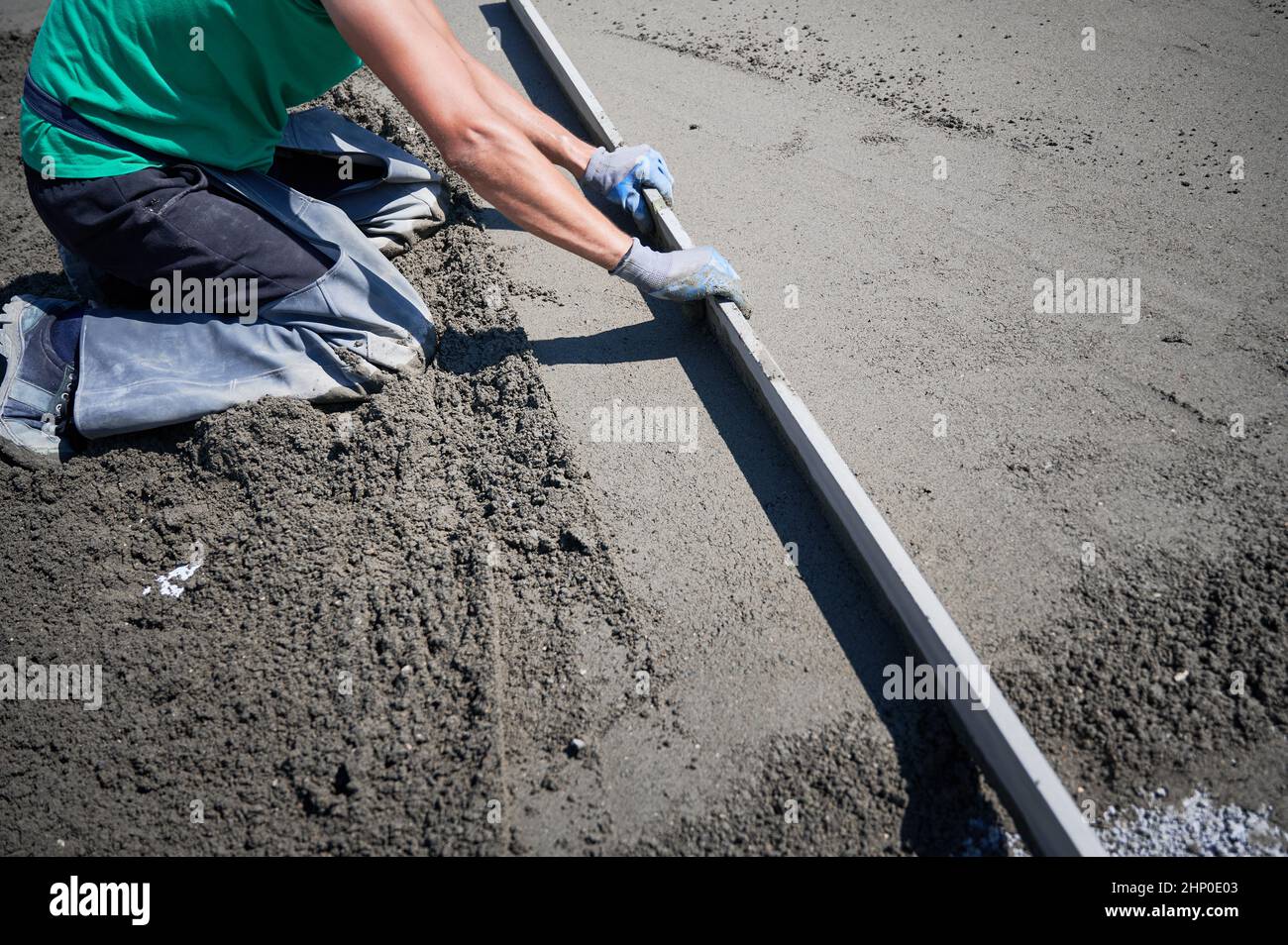 Close up of man builder placing screed rail on the floor covered with ...