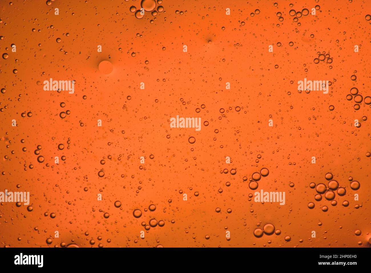 close-up view of a luminous orange liquid background of moving bubbles ...