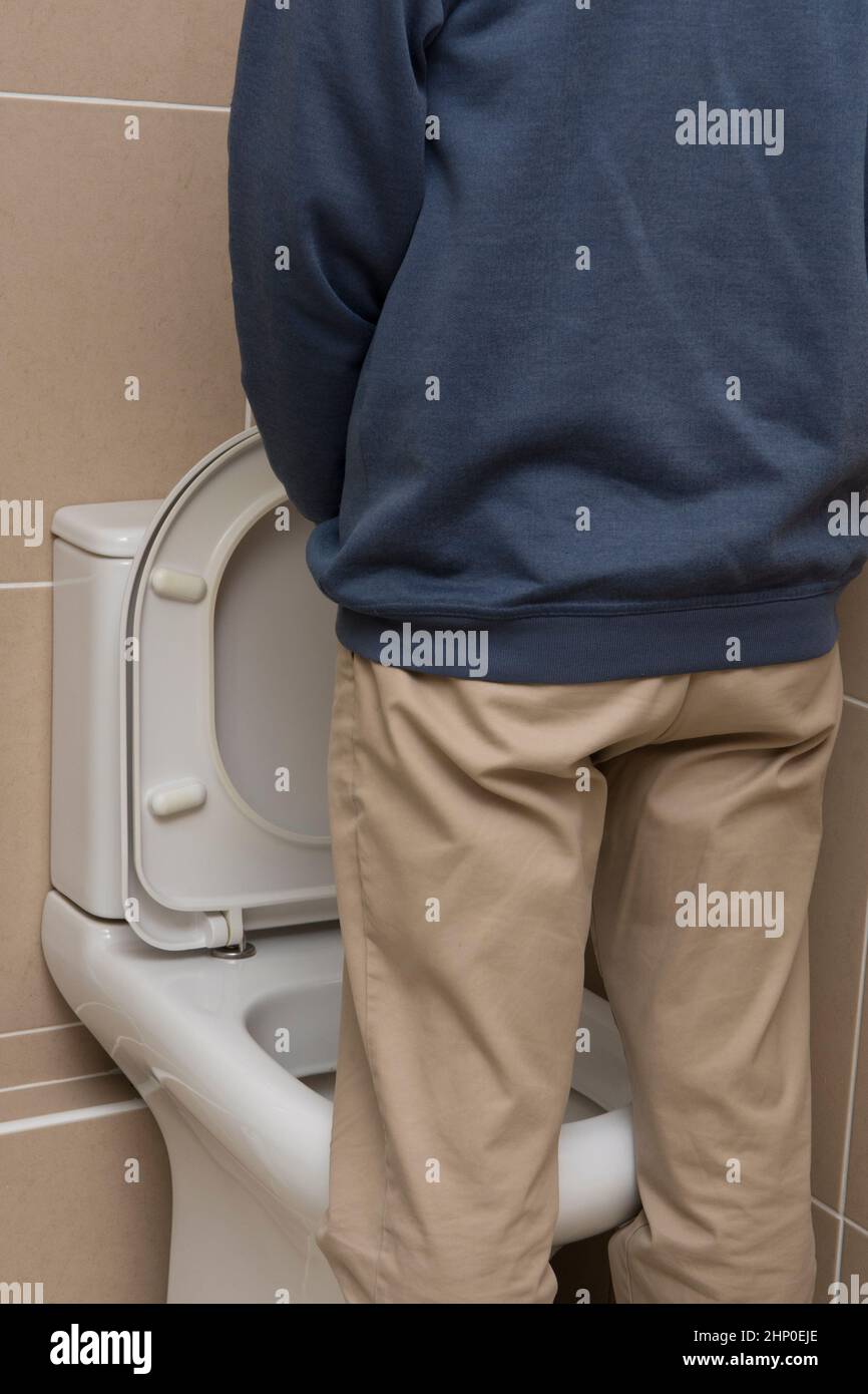 older man with possible prostate problem urinating into toilet, loo ...