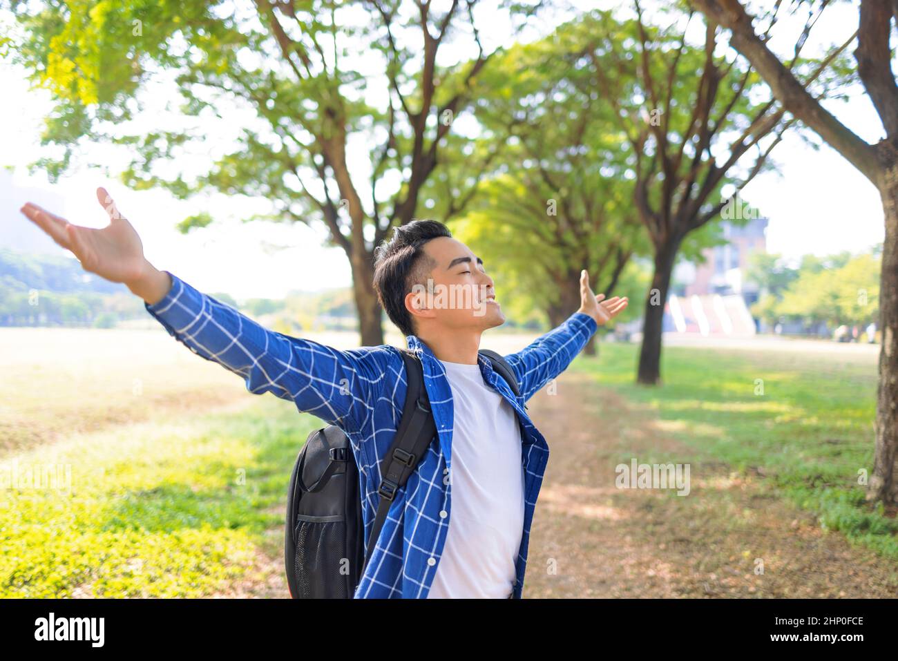 Relaxed young man breathing deeply fresh air in a forest with green ...