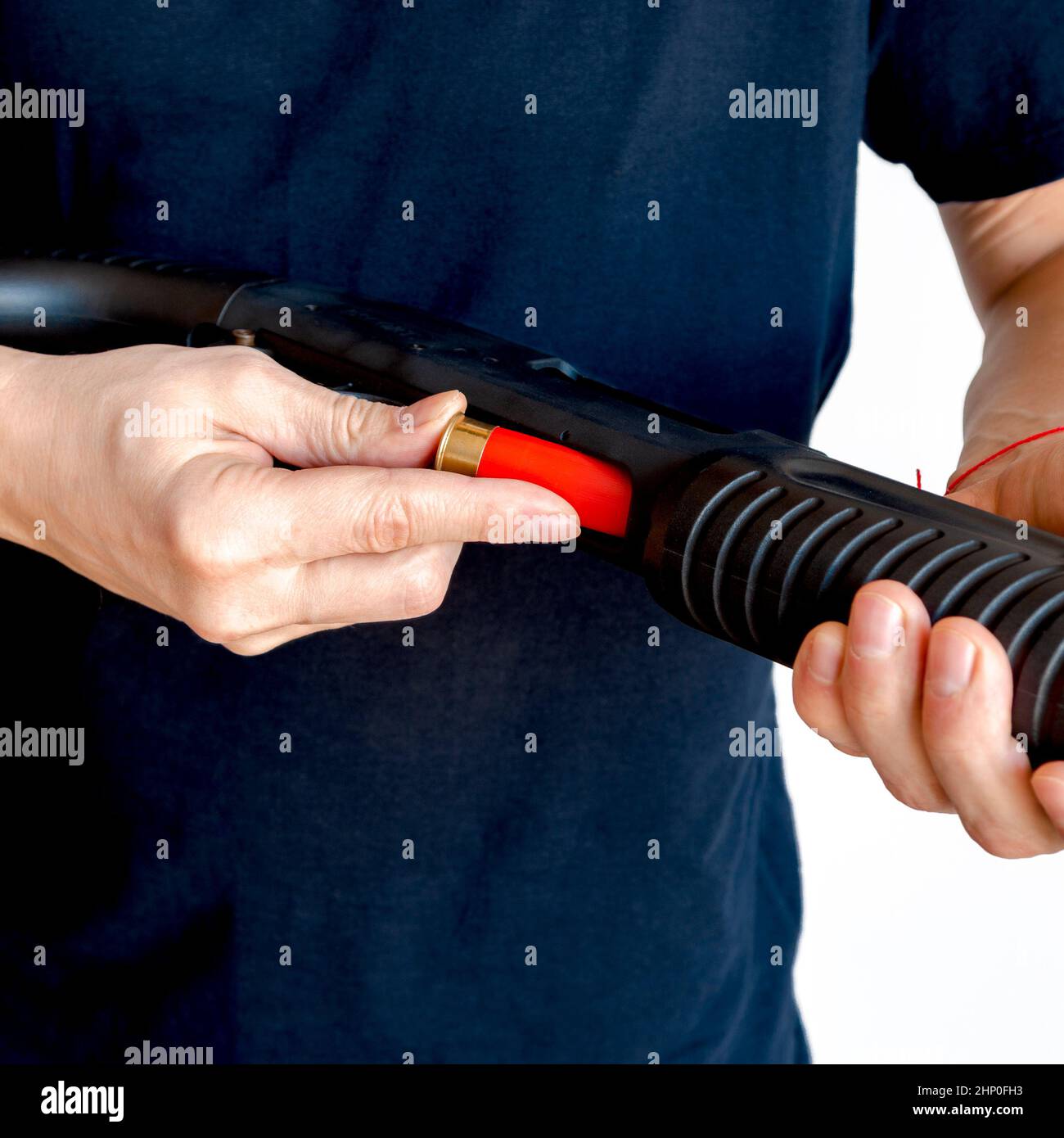 Close up of man loading a red shotgun shell into the magazine of his ...