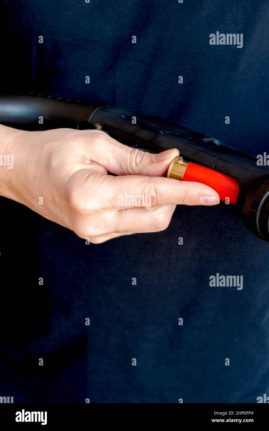 Close up of man loading a red shotgun shell into the magazine of his ...
