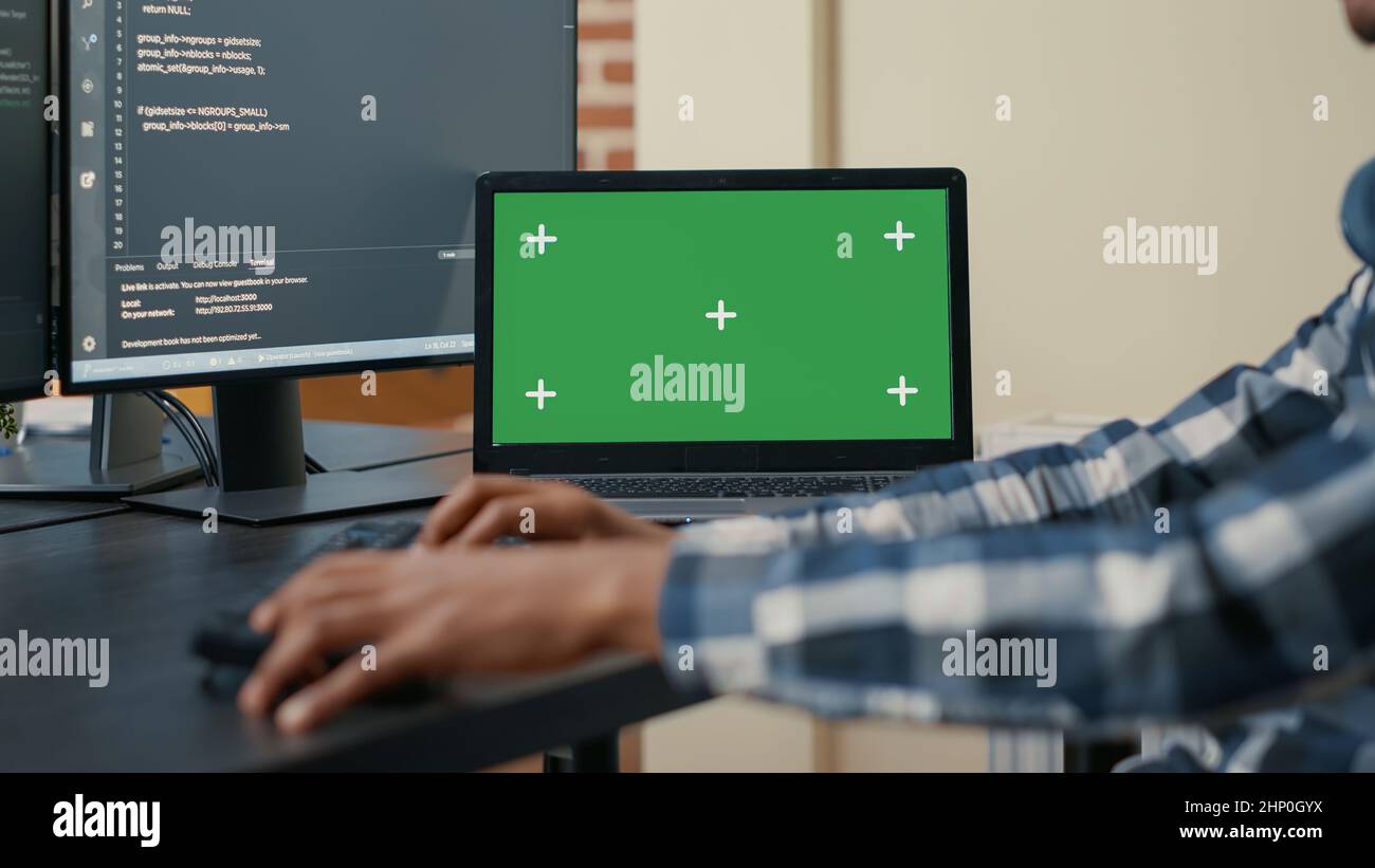 Closeup of laptop with green screen chroma key mockup and african american hands writing code on ...
