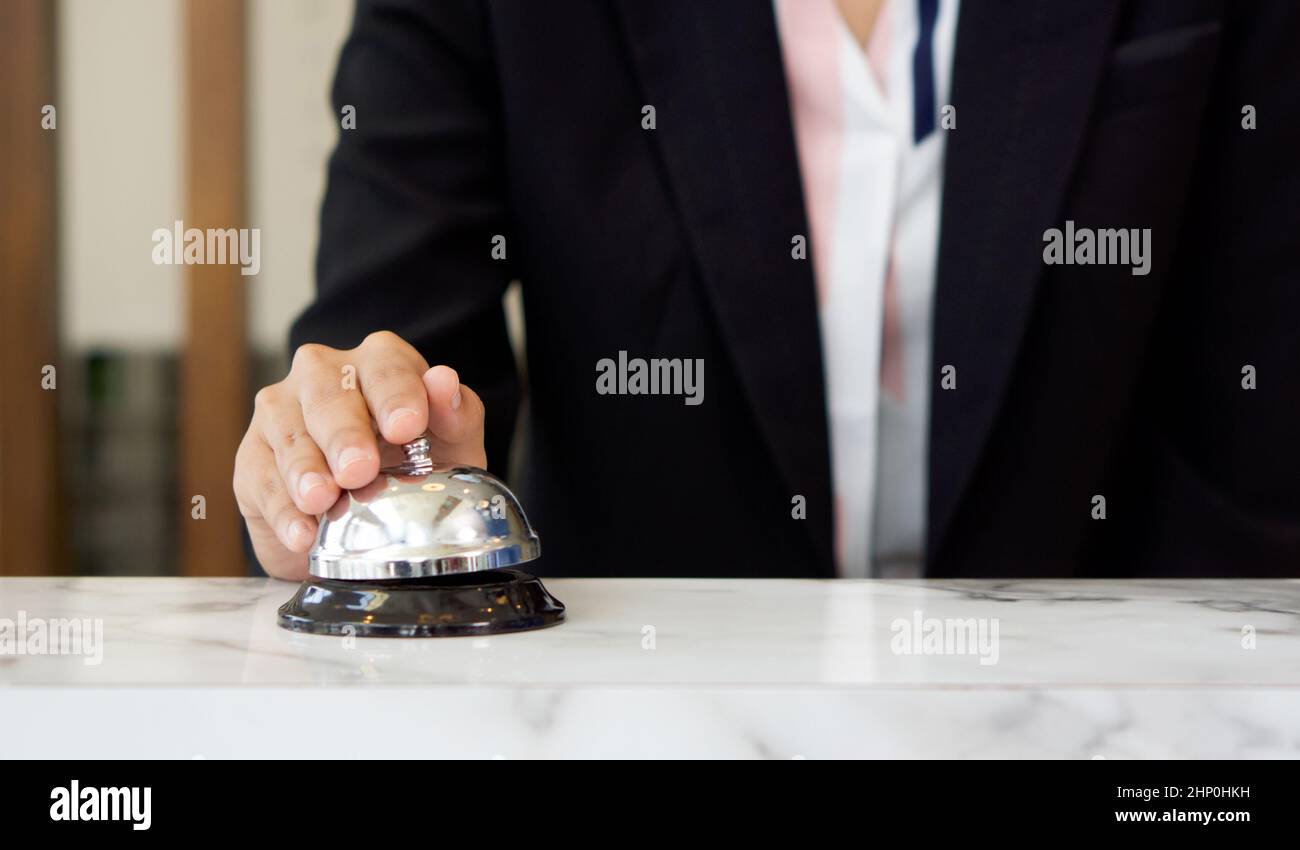 Closeup of a businesswoman hand ringing silver service bell on hotel ...