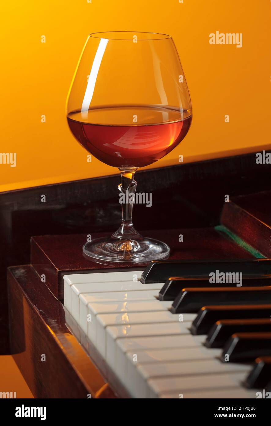 Glass with brandy on an old piano Stock Photo - Alamy