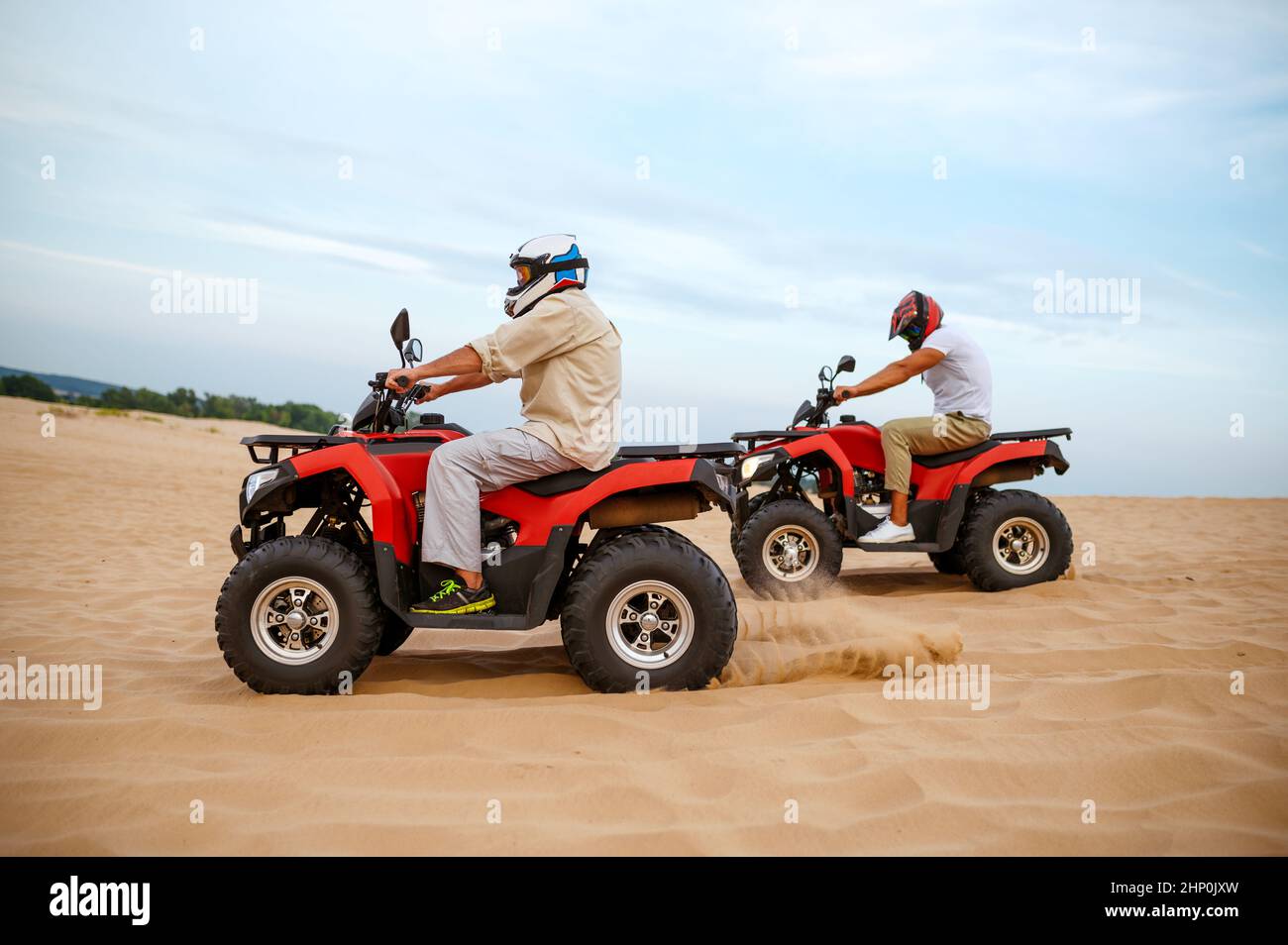 Two atv riders racing in desert sands. Male persons on quad bikes ...