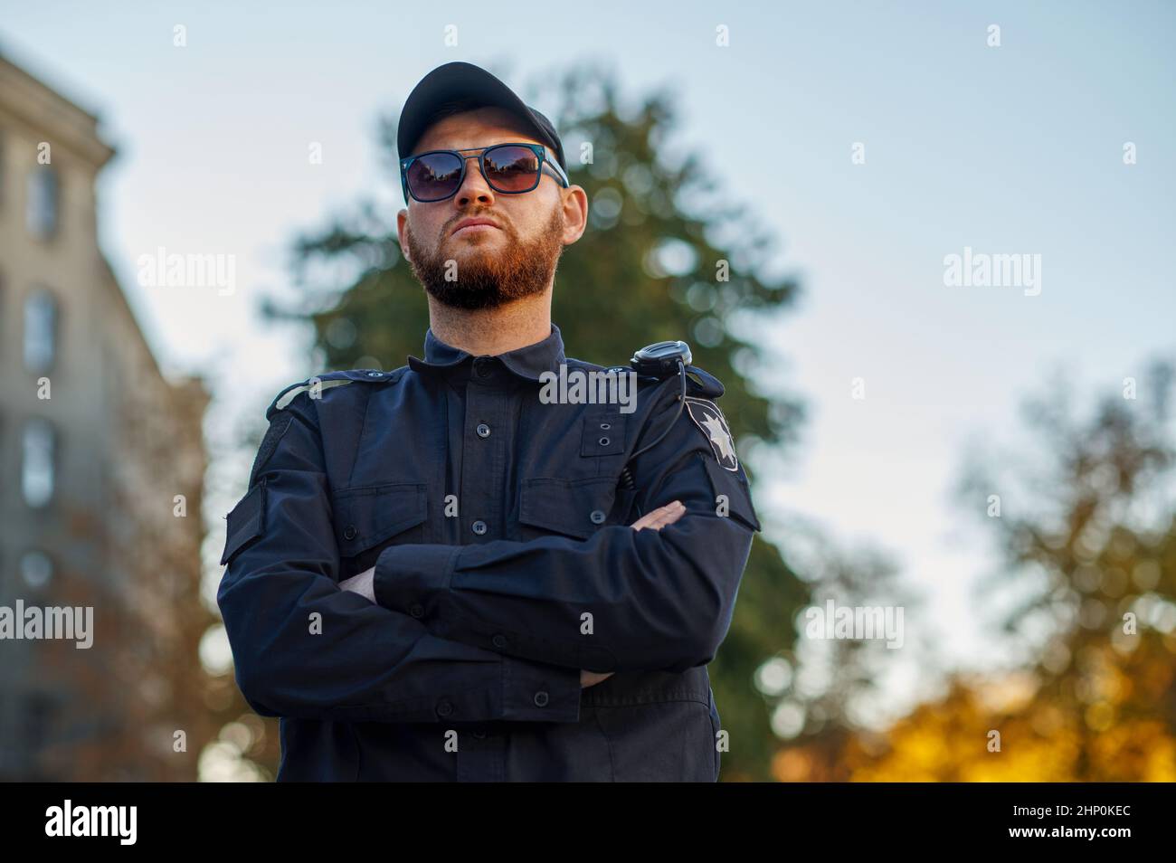 Male police officer poses in uniform and sunglasses. Policeman protect ...