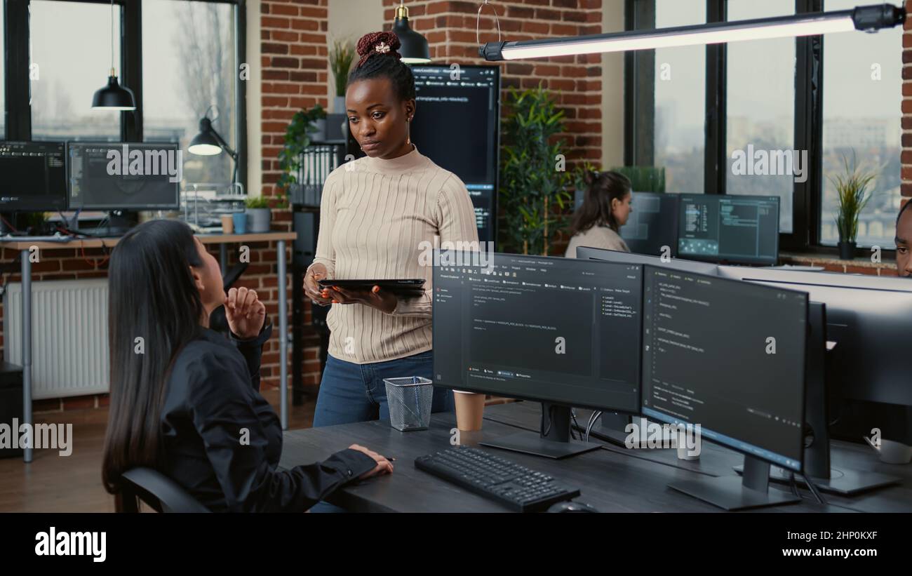 Software developer standing up holding digital tablet talking with ...