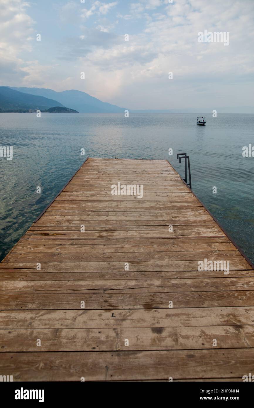 Wood pier pontoon on a lake and a boat Stock Photo - Alamy