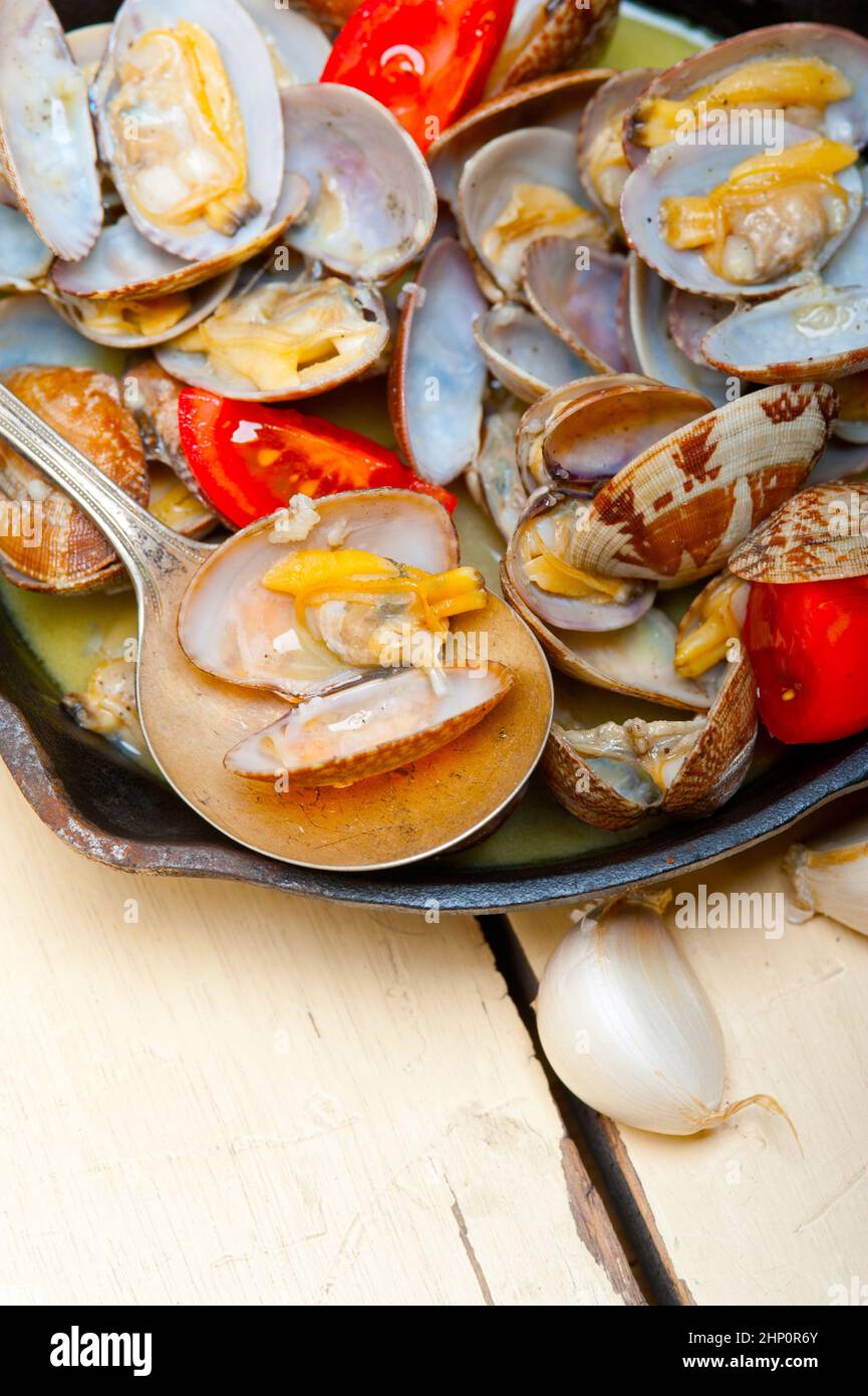 fresh clams stewed on an iron skillet over wite rustic wood table Stock ...