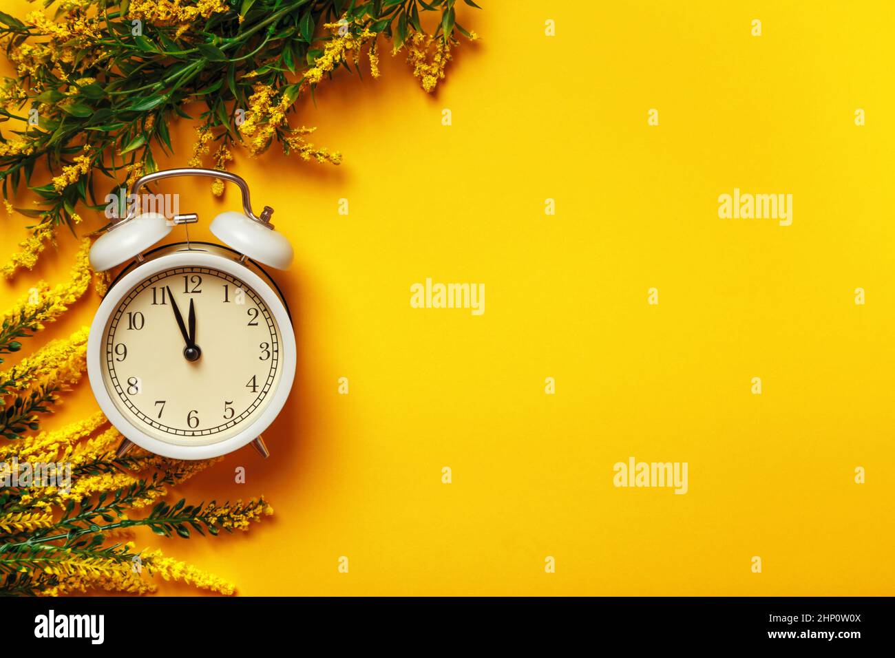 Spring time change. Retro alarm clock with flowering branches on a ...