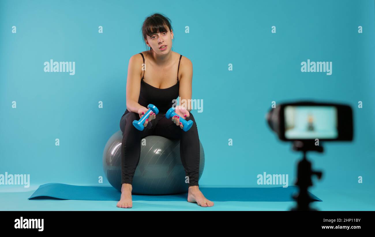 Fitness vlogger recording workout video on camera in studio, using ...