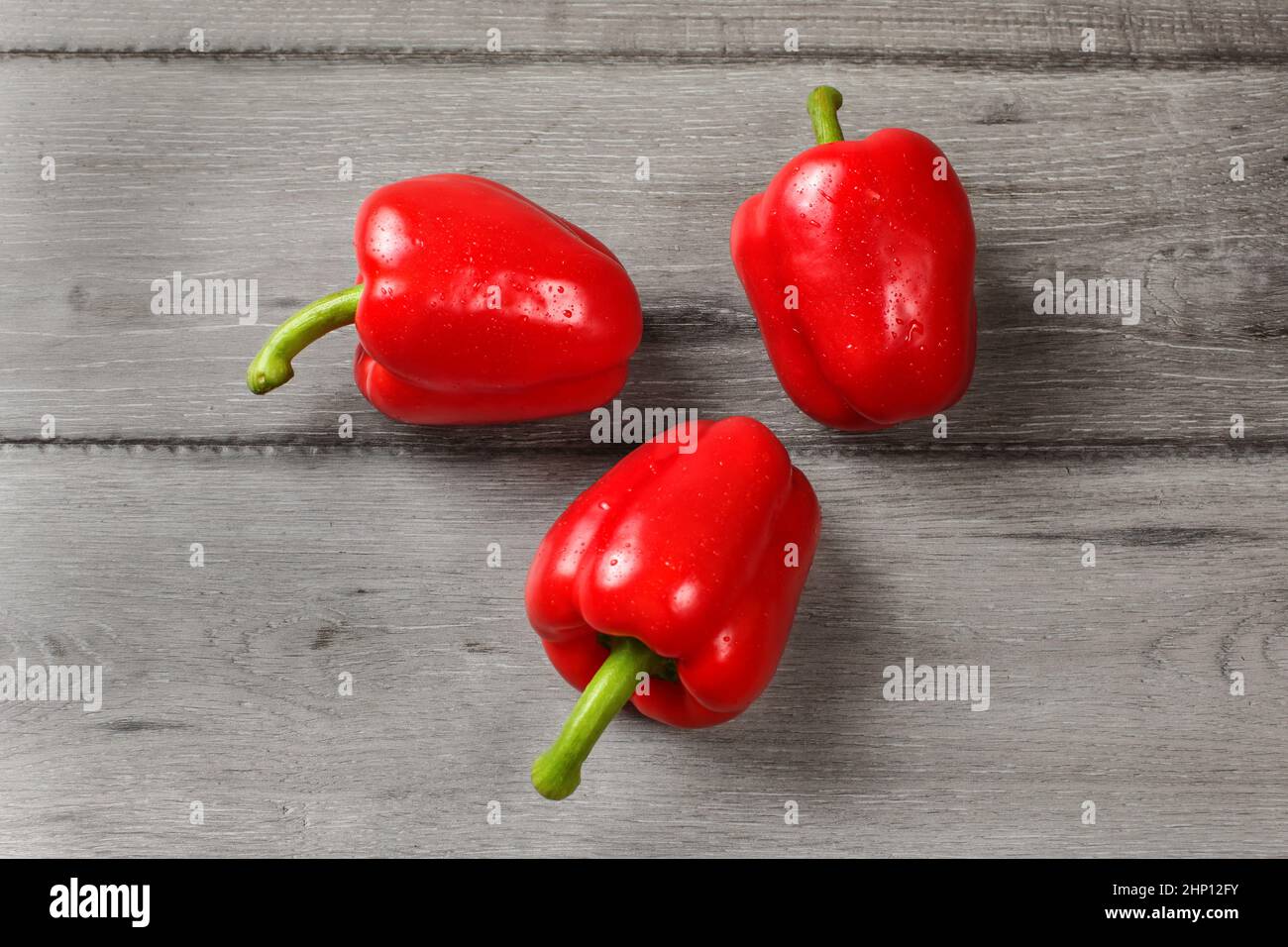 Tabletop view - three red bell peppers on rustic gray wood desk Stock ...