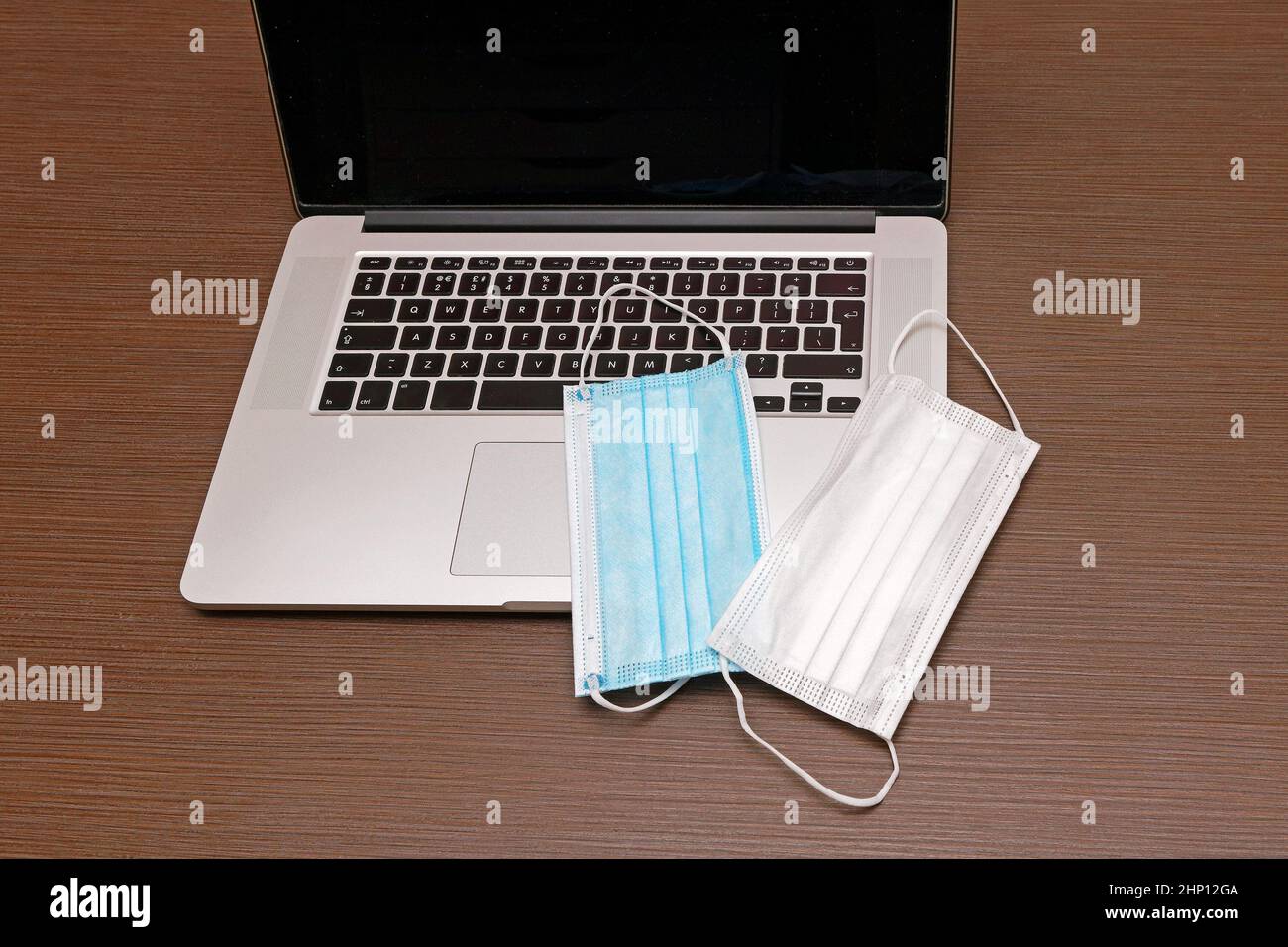 Open laptop with face masks on keyboard for employees working inside ...
