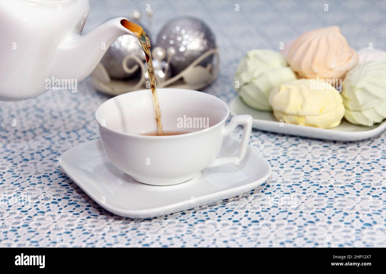Tea party time. Hostess pours tea into cups from the kettle, in a piece ...