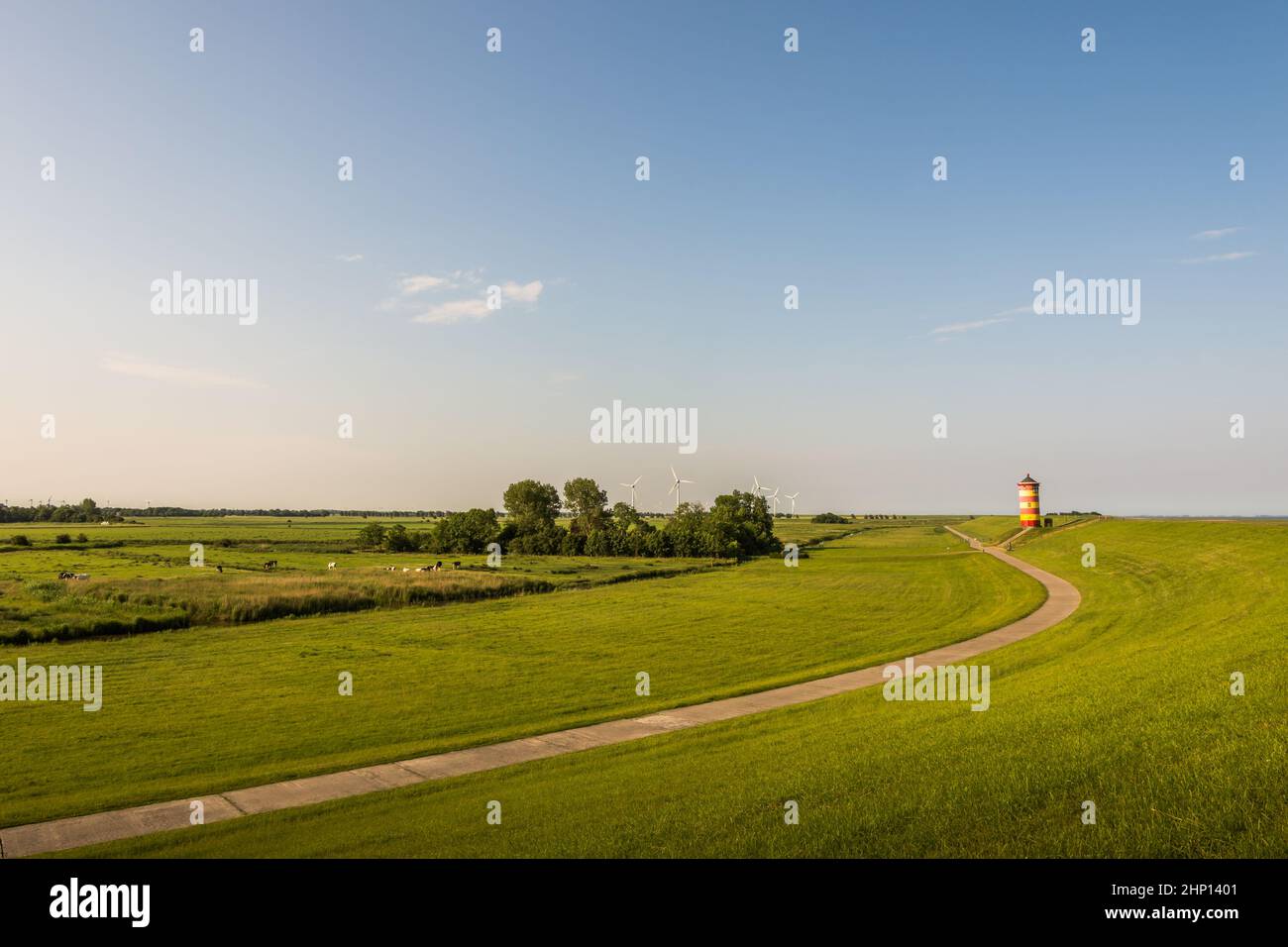 Green dike landscape at the Pilsum lighthouse with wind turbines on the ...